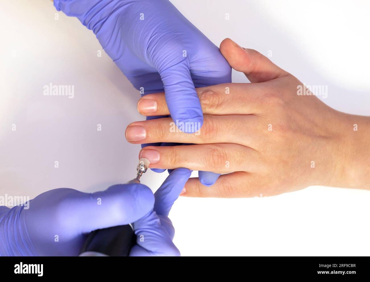 Nail beautician gloss client's fingernails by rubbing beeswax cream ...