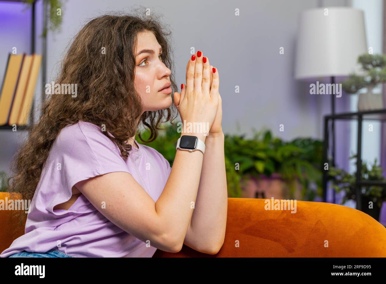 Please, God help. Young woman praying sincerely with folded arms ...