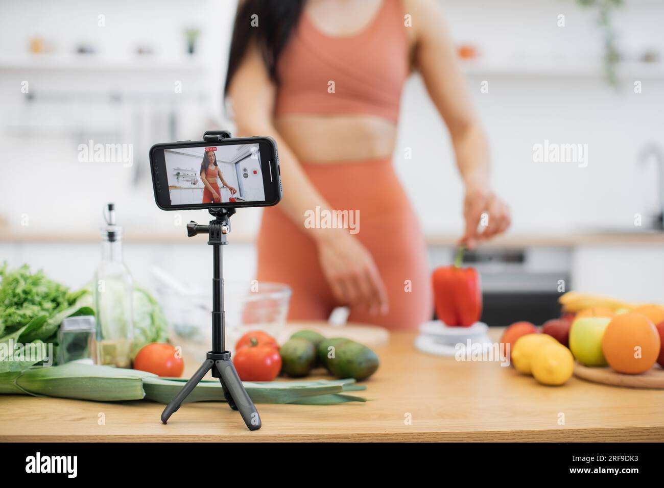 Focus on modern cell phone stabilized by tripod on kitchen table among ...