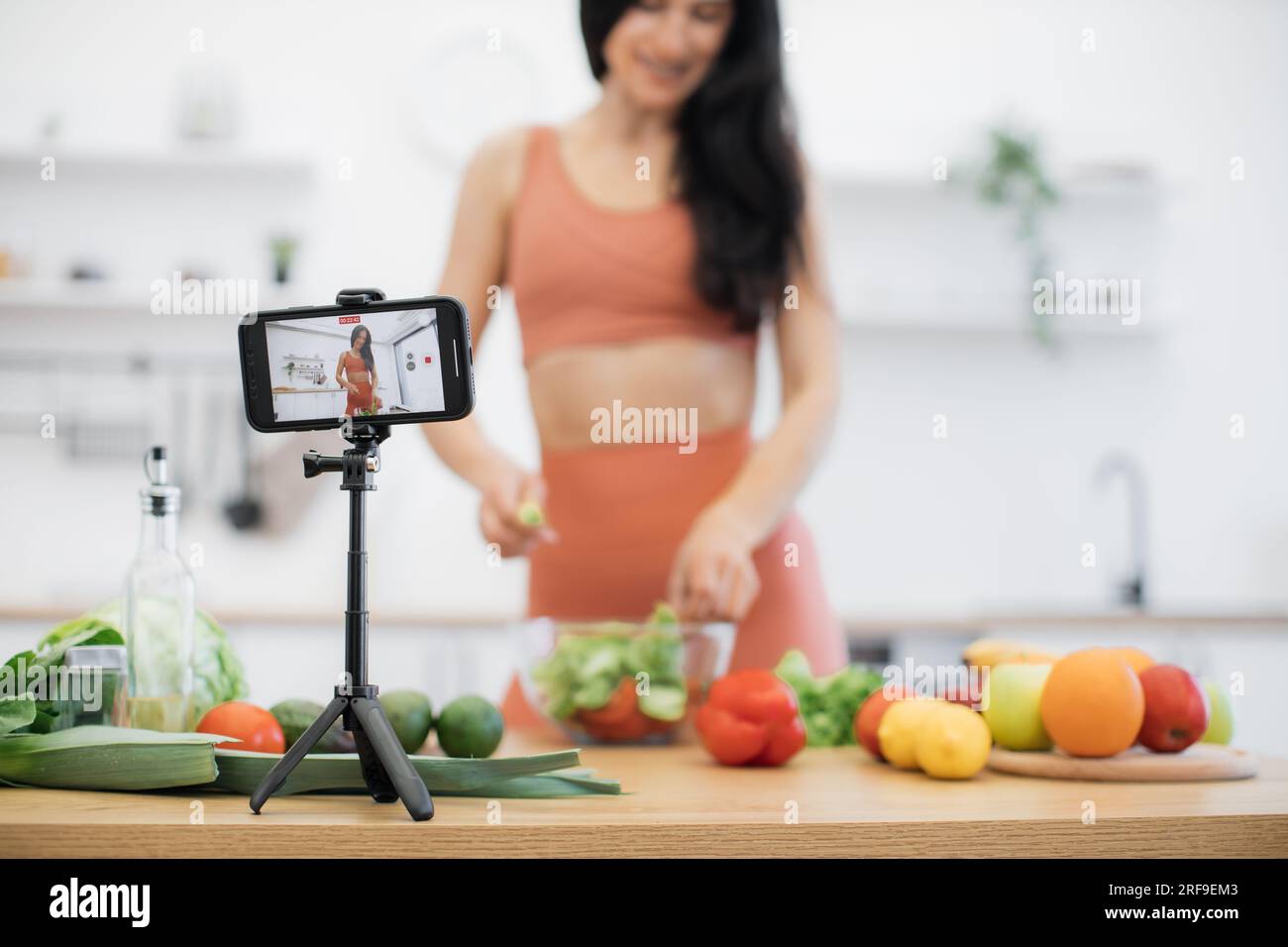 Focus on handheld device on tripod shooting attractive lady putting ...