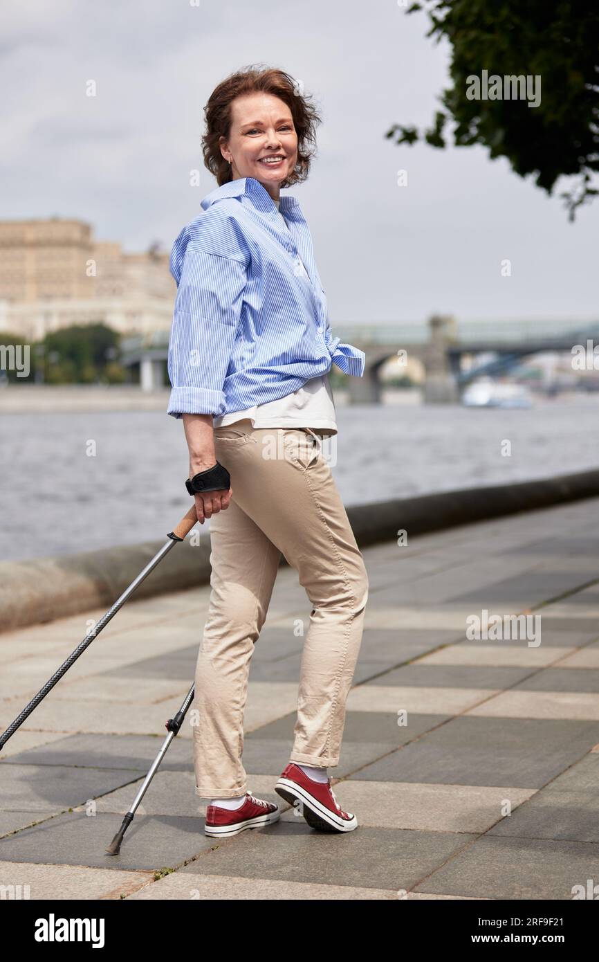 Attractive mature woman with nordic walking poles. Senior lady walking ...