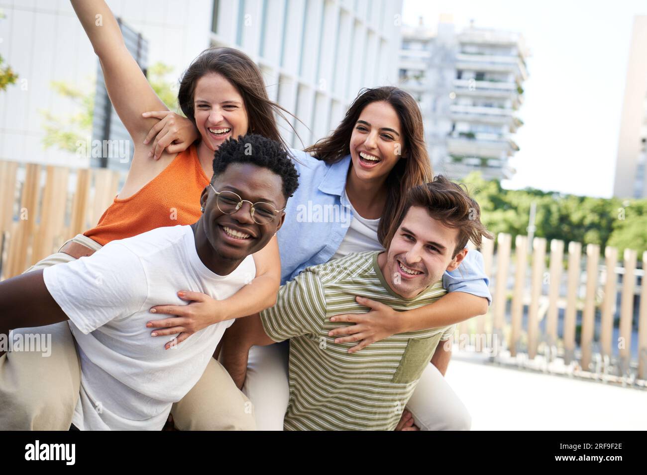 Group of joyful multicultural friends united celebrating and piggyback ...