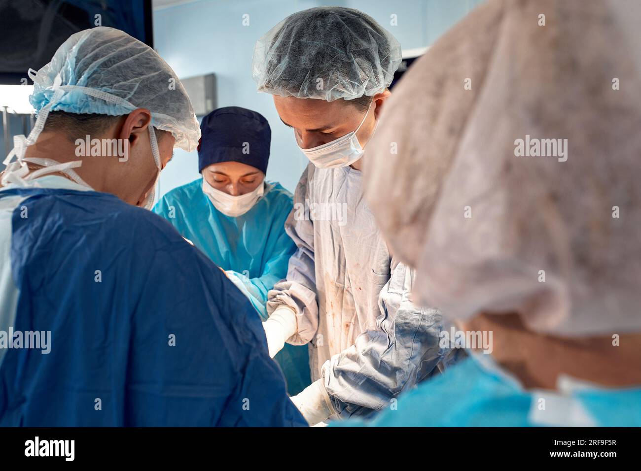 Portrait of surgeons leaned over patient during complex surgical ...