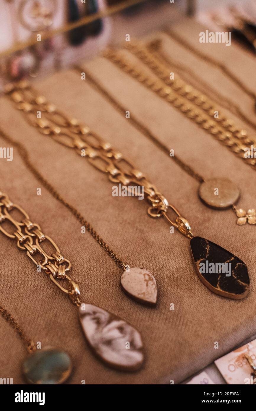Golden chain jewelry, necklace with marble stones on the beige showcase ...