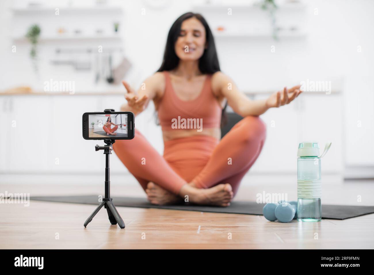 Professional female trainer recording video using tripod and smartphone ...