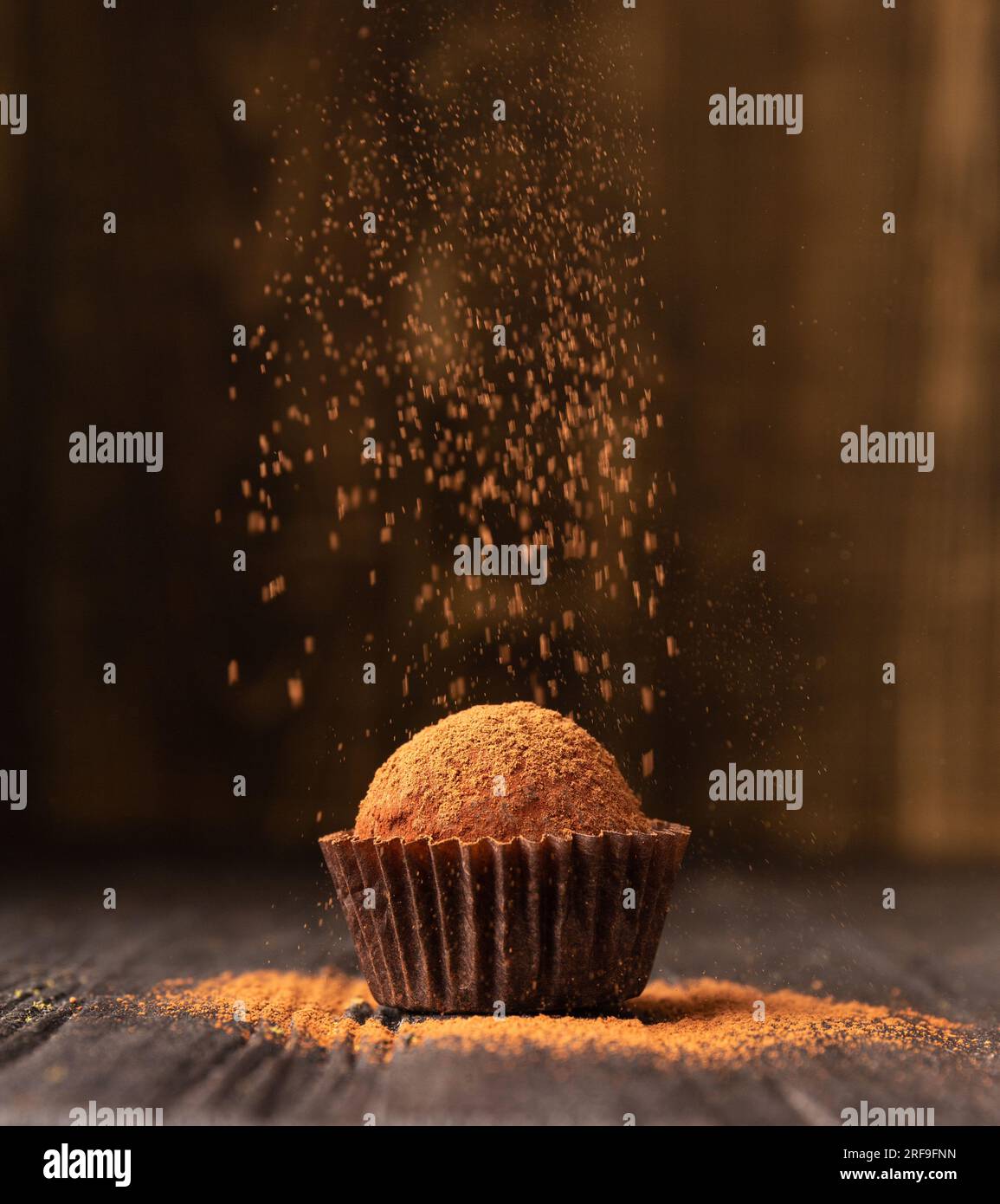 Cocoa powder is sprinkled on a chocolate truffle under a beautiful ...
