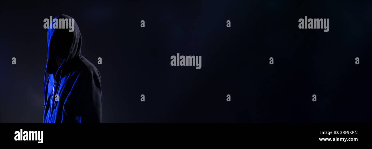 Anonymous man in hood on black background, space for text. Banner ...