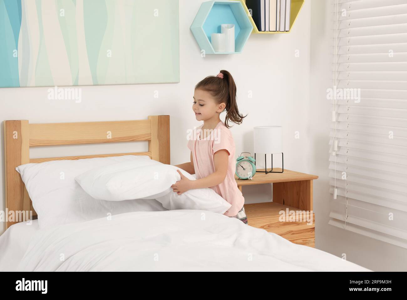 Cute girl changing bed linens in children room Stock Photo - Alamy