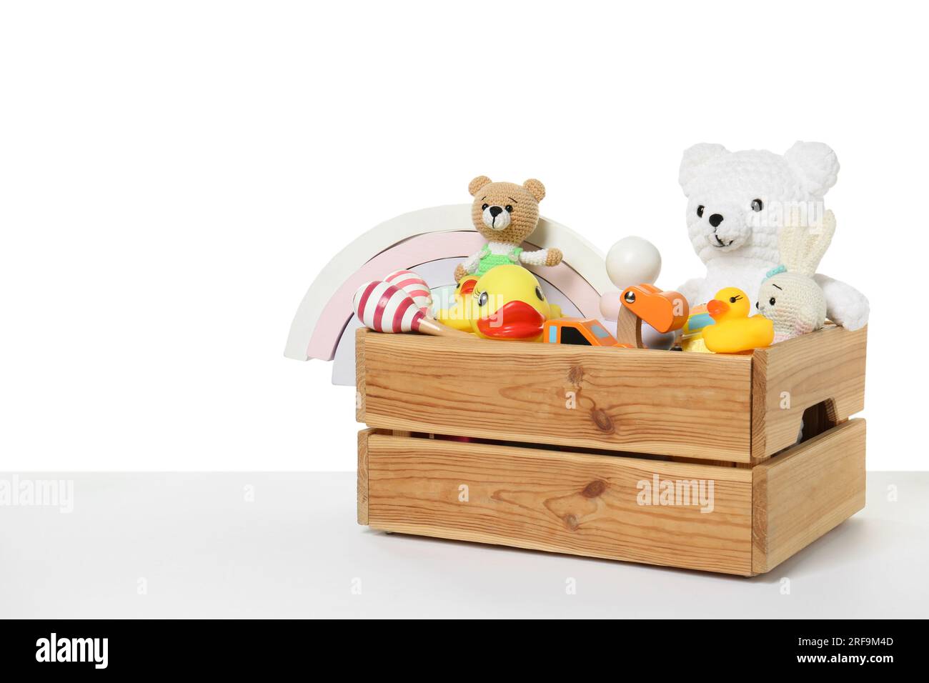 Wooden crate with different children's toys on table against white ...