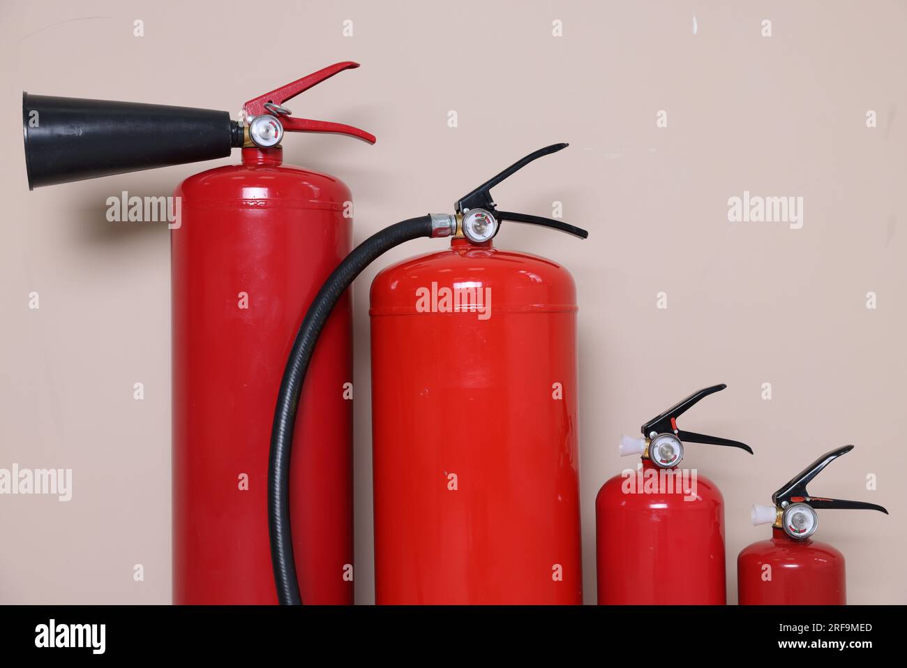 Set of fire extinguishers on beige background Stock Photo - Alamy