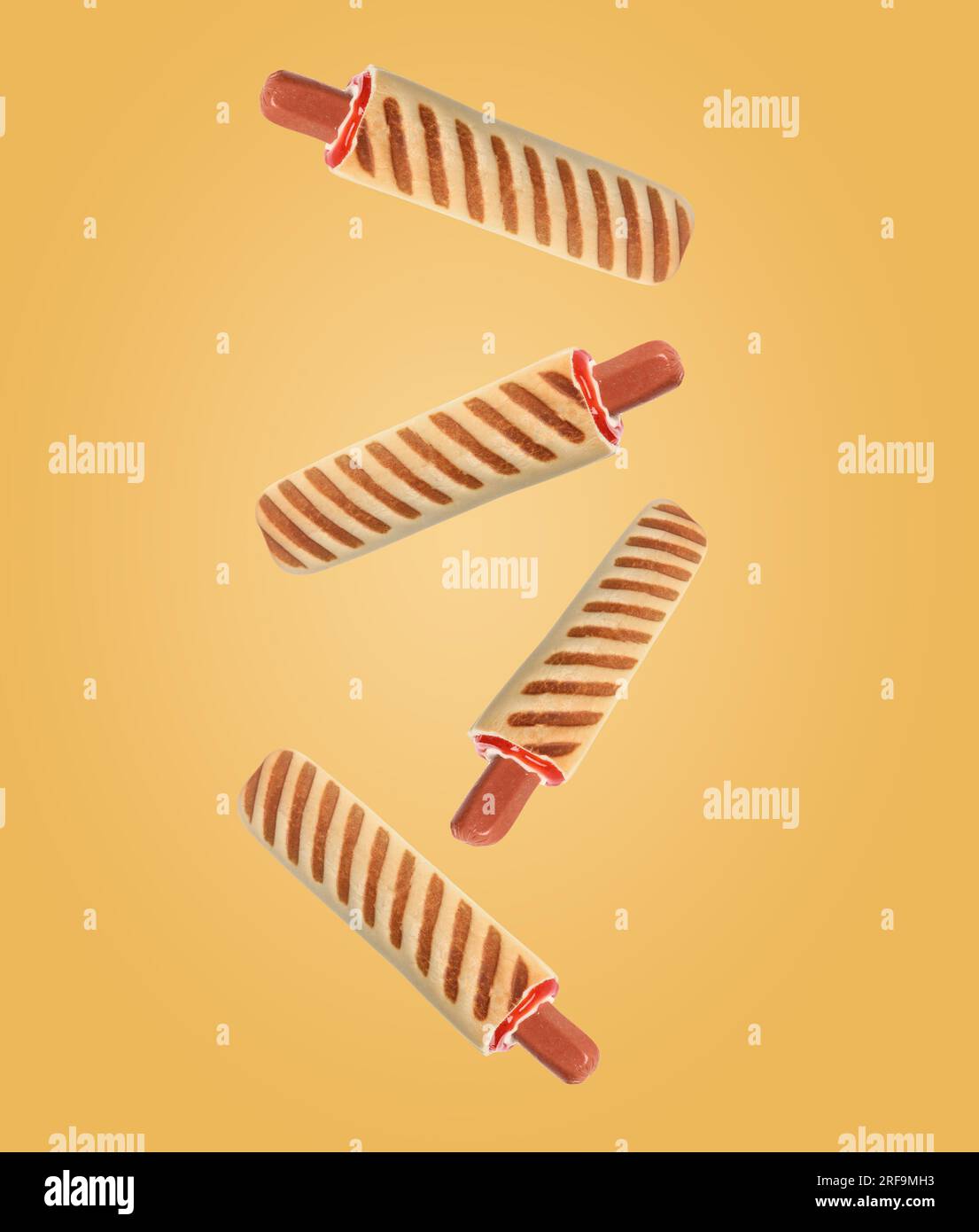 Yummy French hot dogs with grilled buns falling on goldenrod background ...