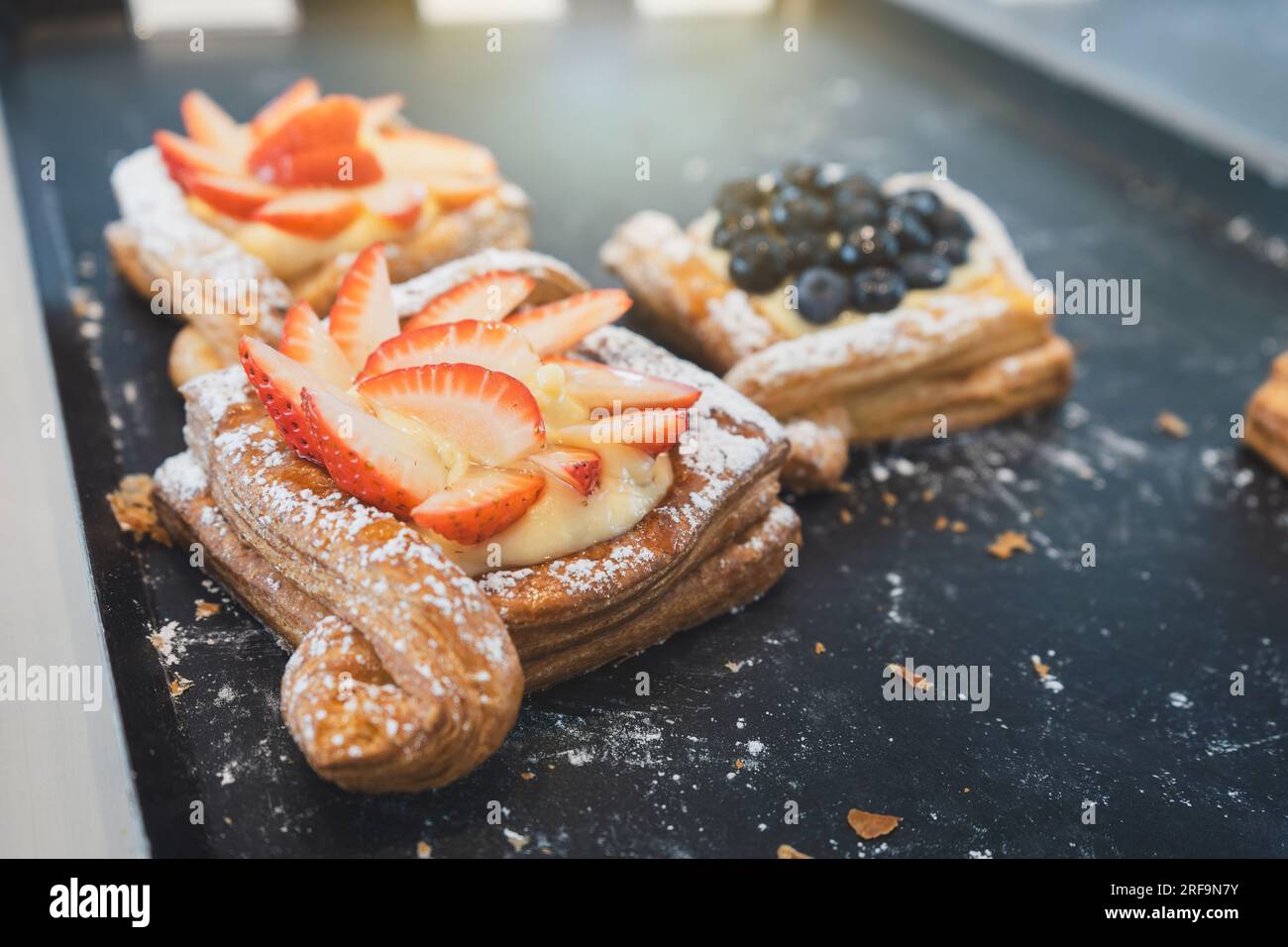Danish strawberry and blueberry on a black tray sold in pastry shop ...