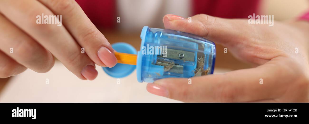 Woman sharpening pencil with sharpener while working in art studio or ...