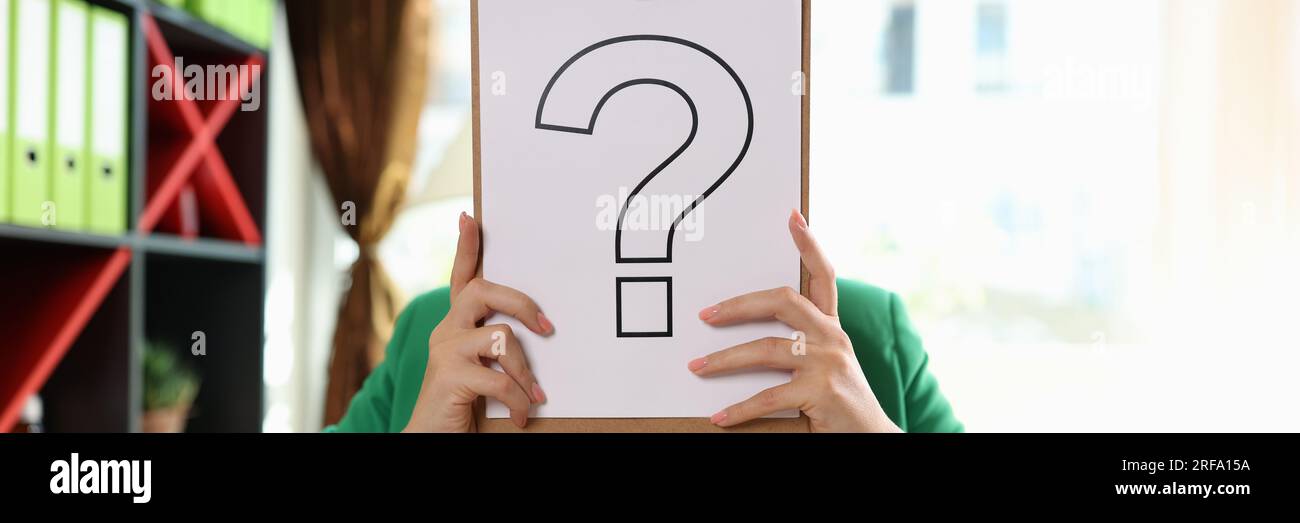 Business woman holding question mark in front of her face in office ...