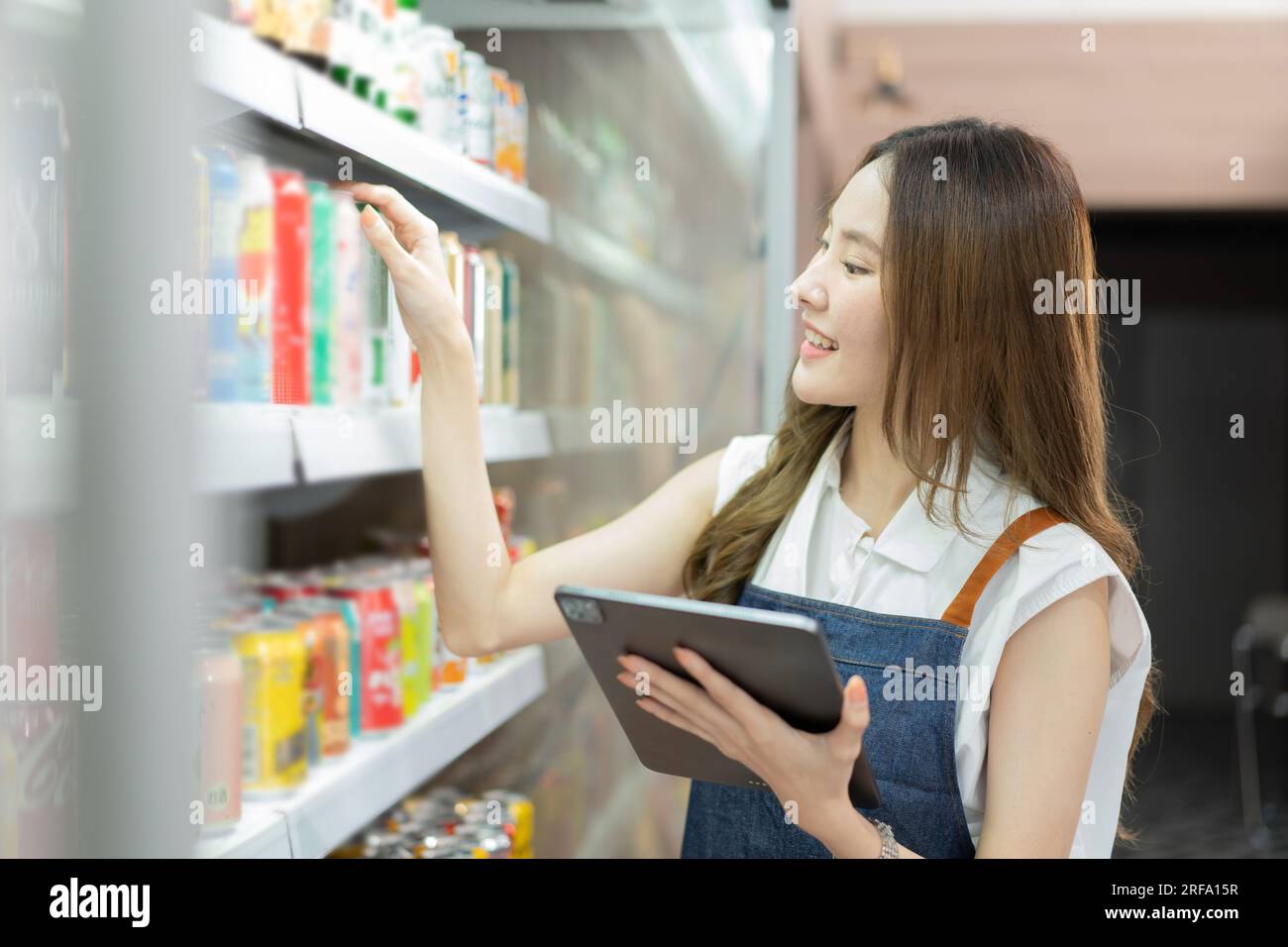 Young Asian supermarket shop employee checking item quality while ...