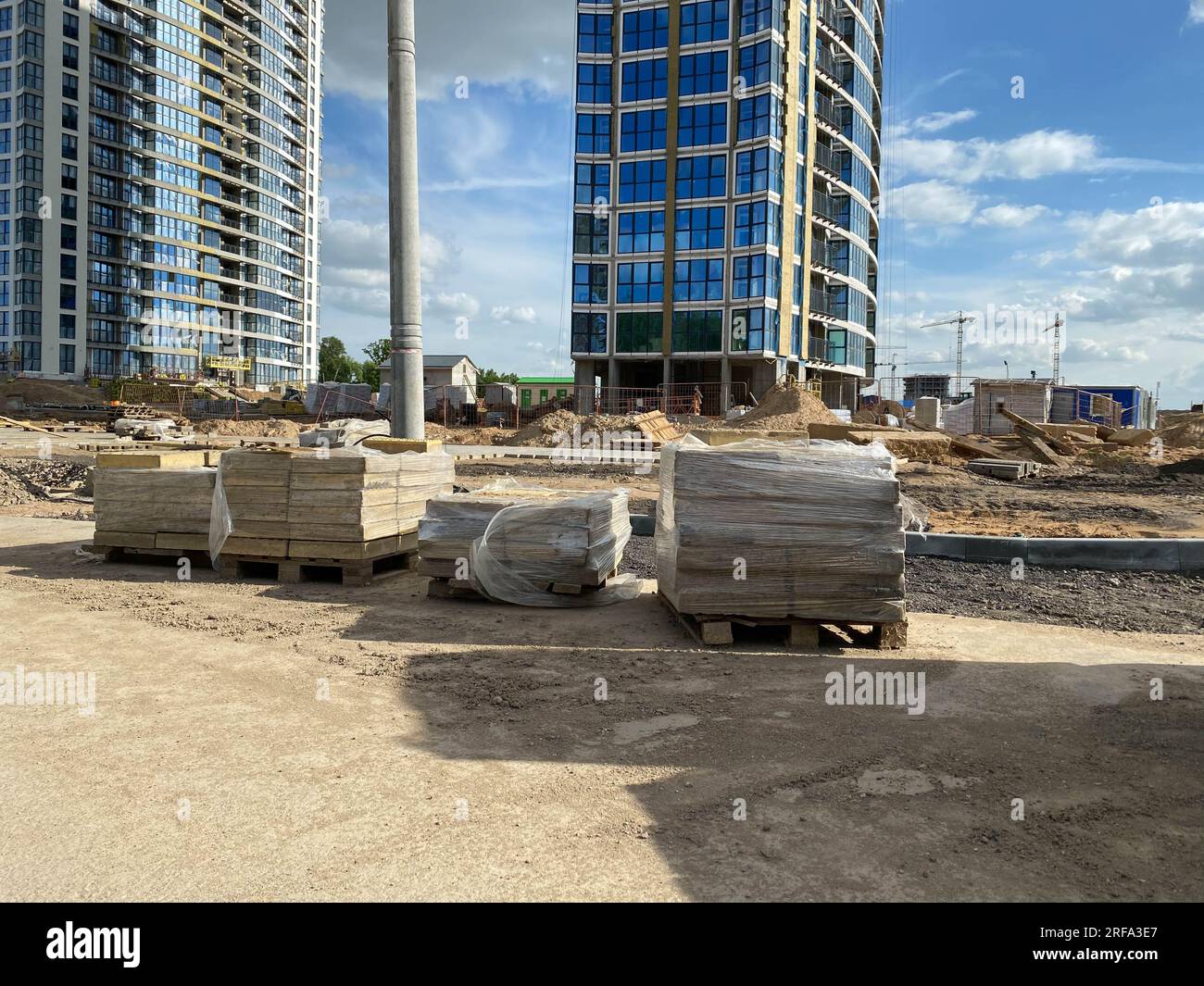 Building materials, paving slabs and curbs lie in front of modern new ...