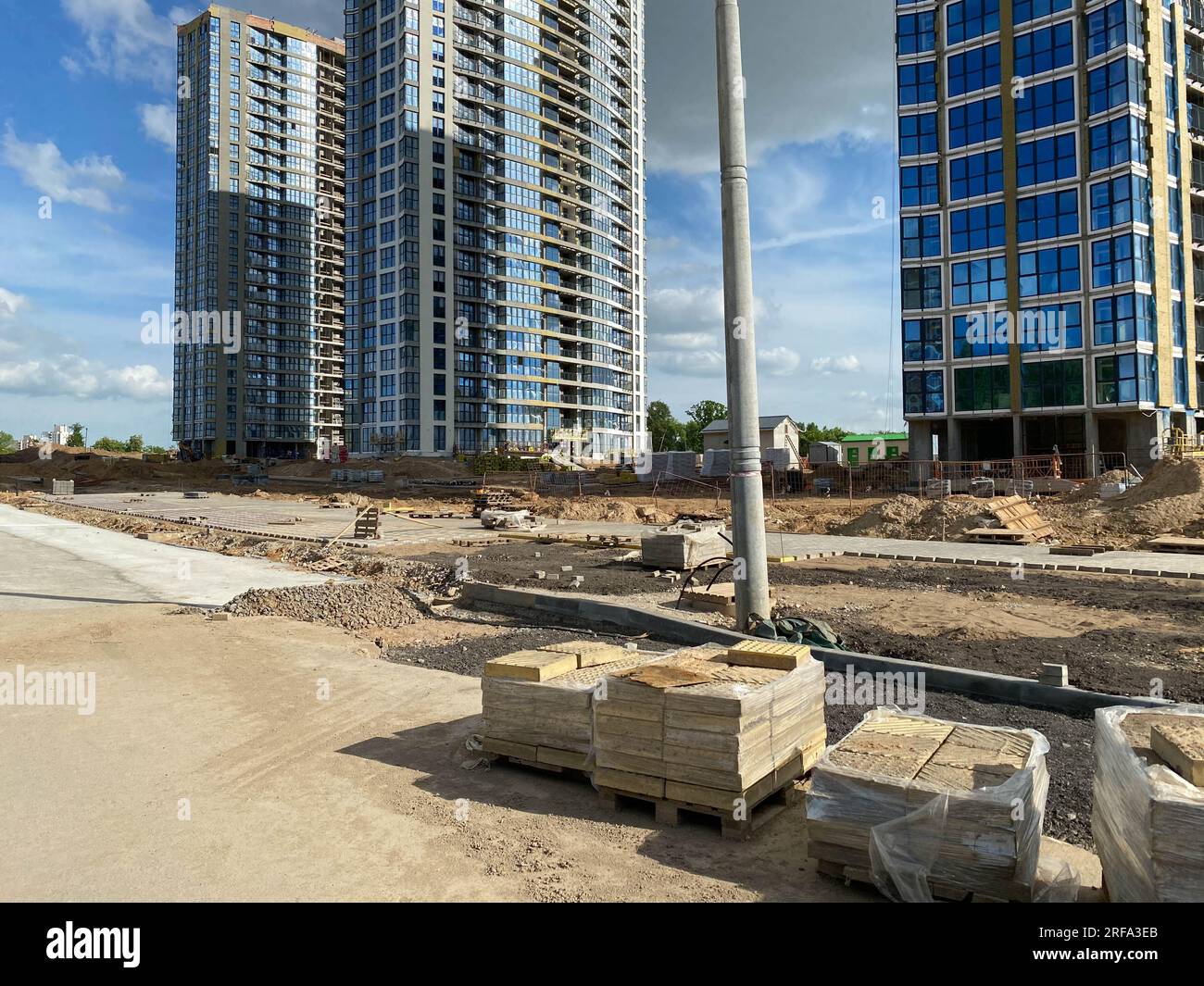 Building materials, paving slabs and curbs lie in front of modern new ...