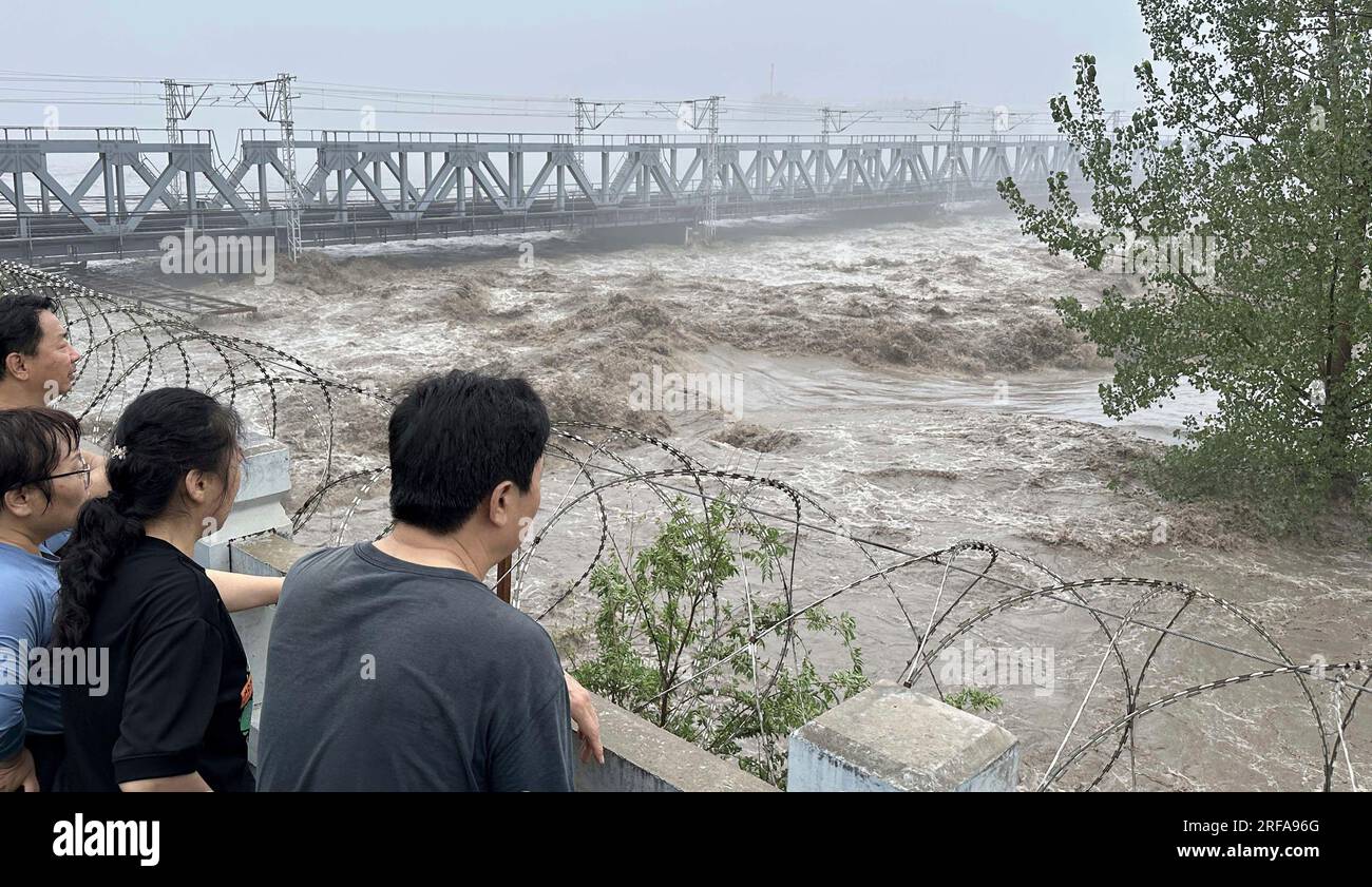 Local residents watch a flood-swollen river in the suburbs of Beijing ...