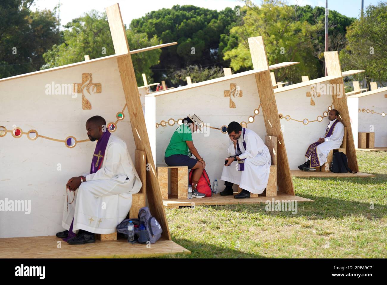 A priest listens to confession in a row of confessionals set up for ...