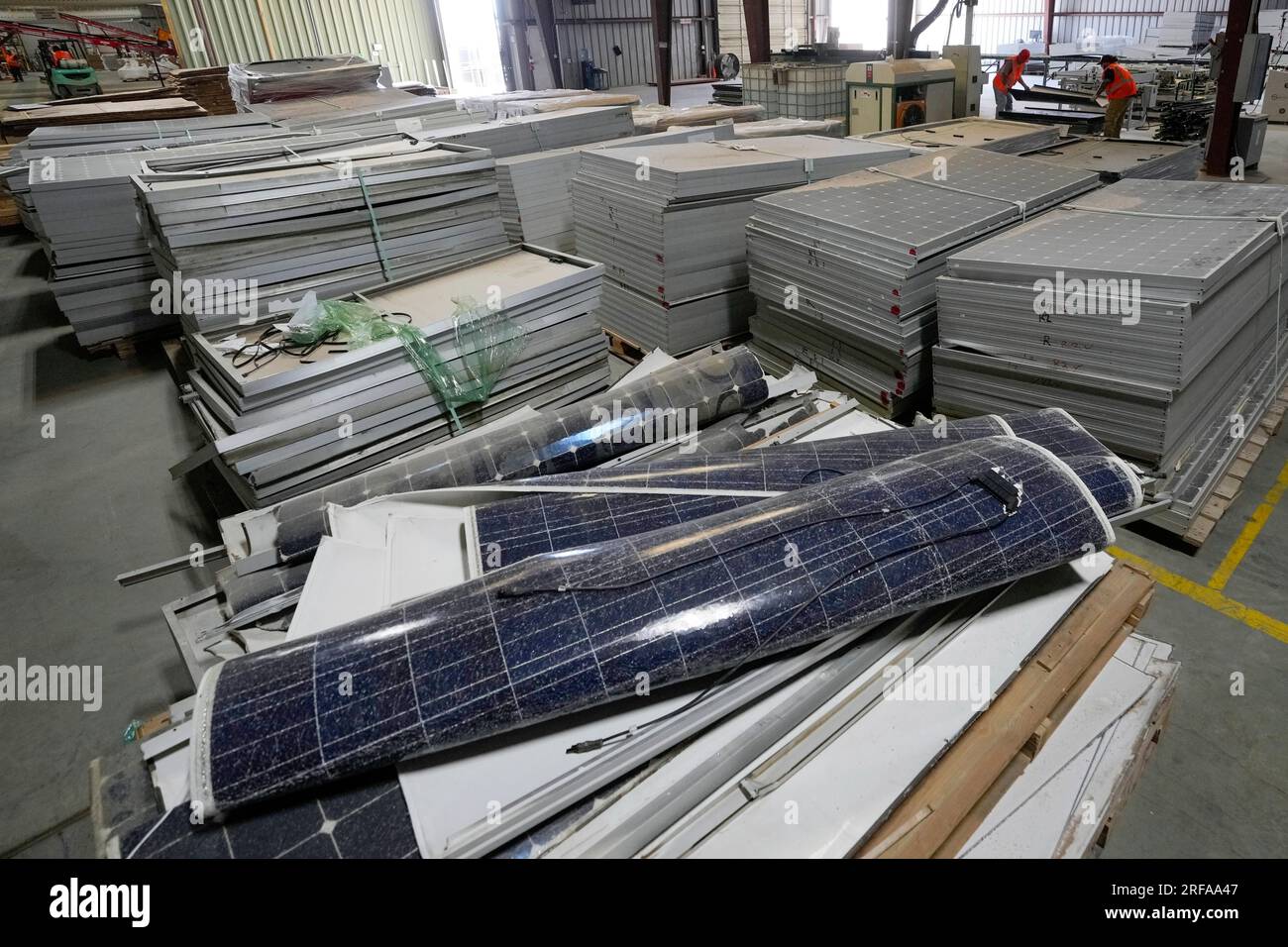 Workers take apart solar panels as they begin the recycling process at ...