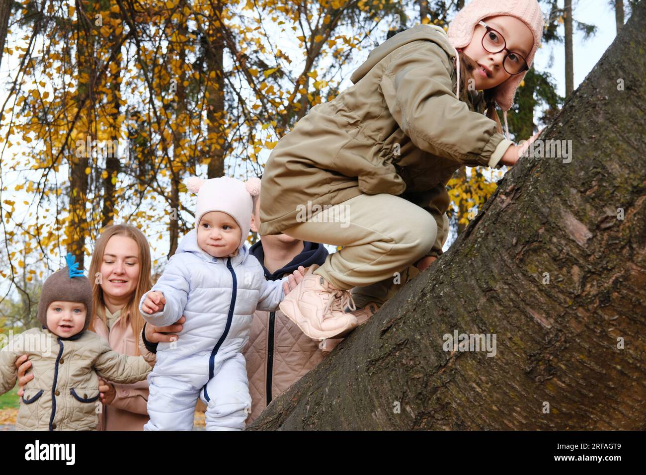 A large family spends time together in the park. Children try to climb ...