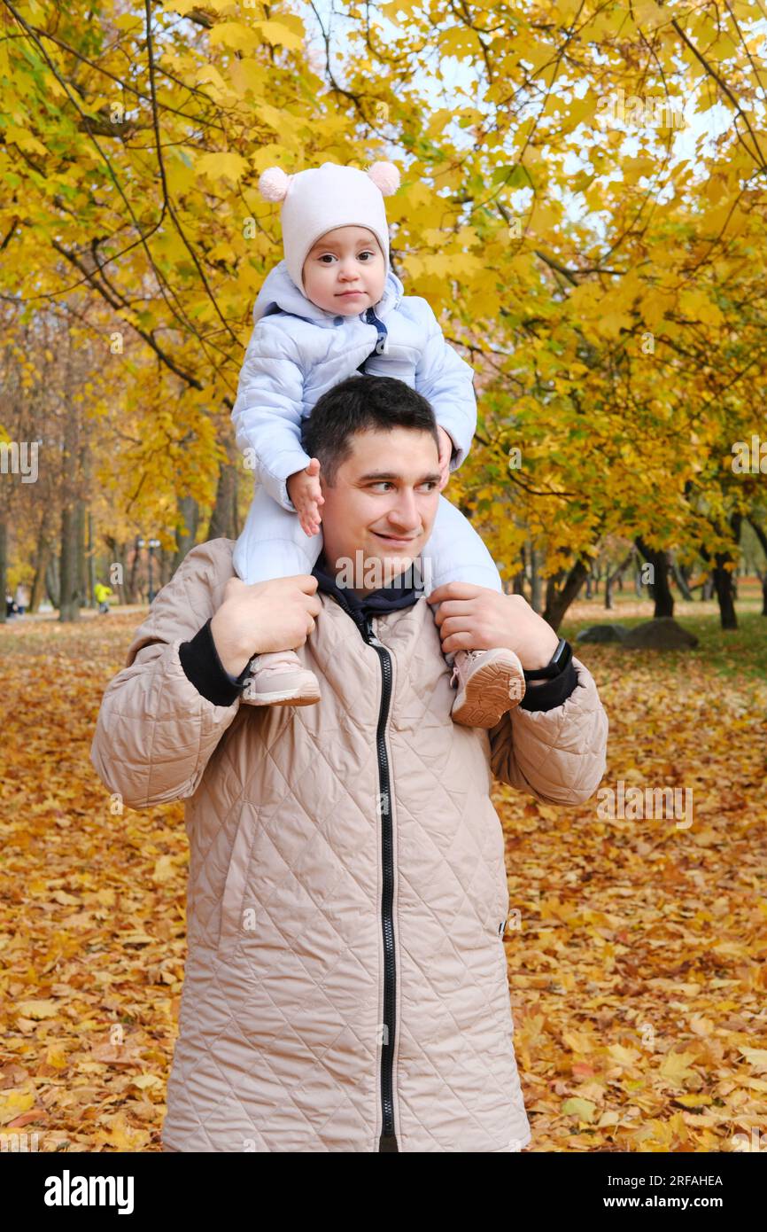 Portrait of a father carrying his cute little daughter on shoulders ...
