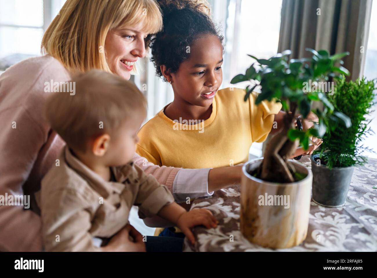 Young woman with her children taking care of plants indoors. Family ...