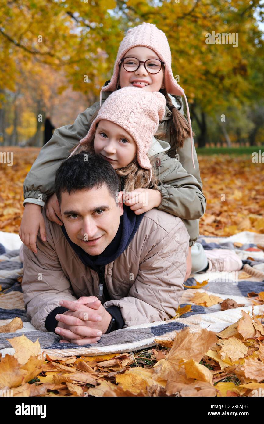 Father with children lying down on a blanket making a human pyramid in ...