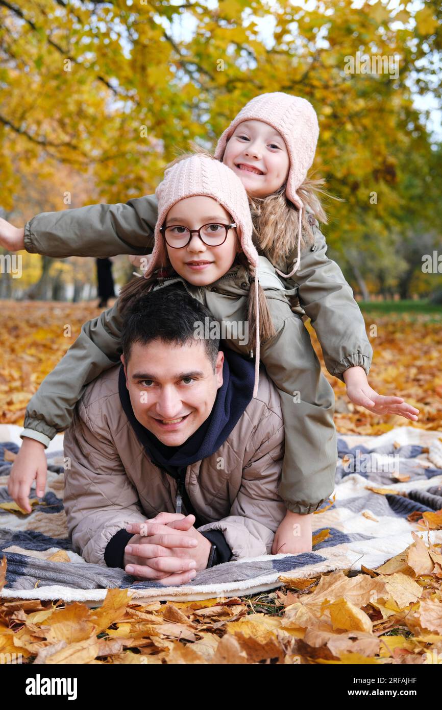 Father with children lying down on a blanket making a human pyramid in ...