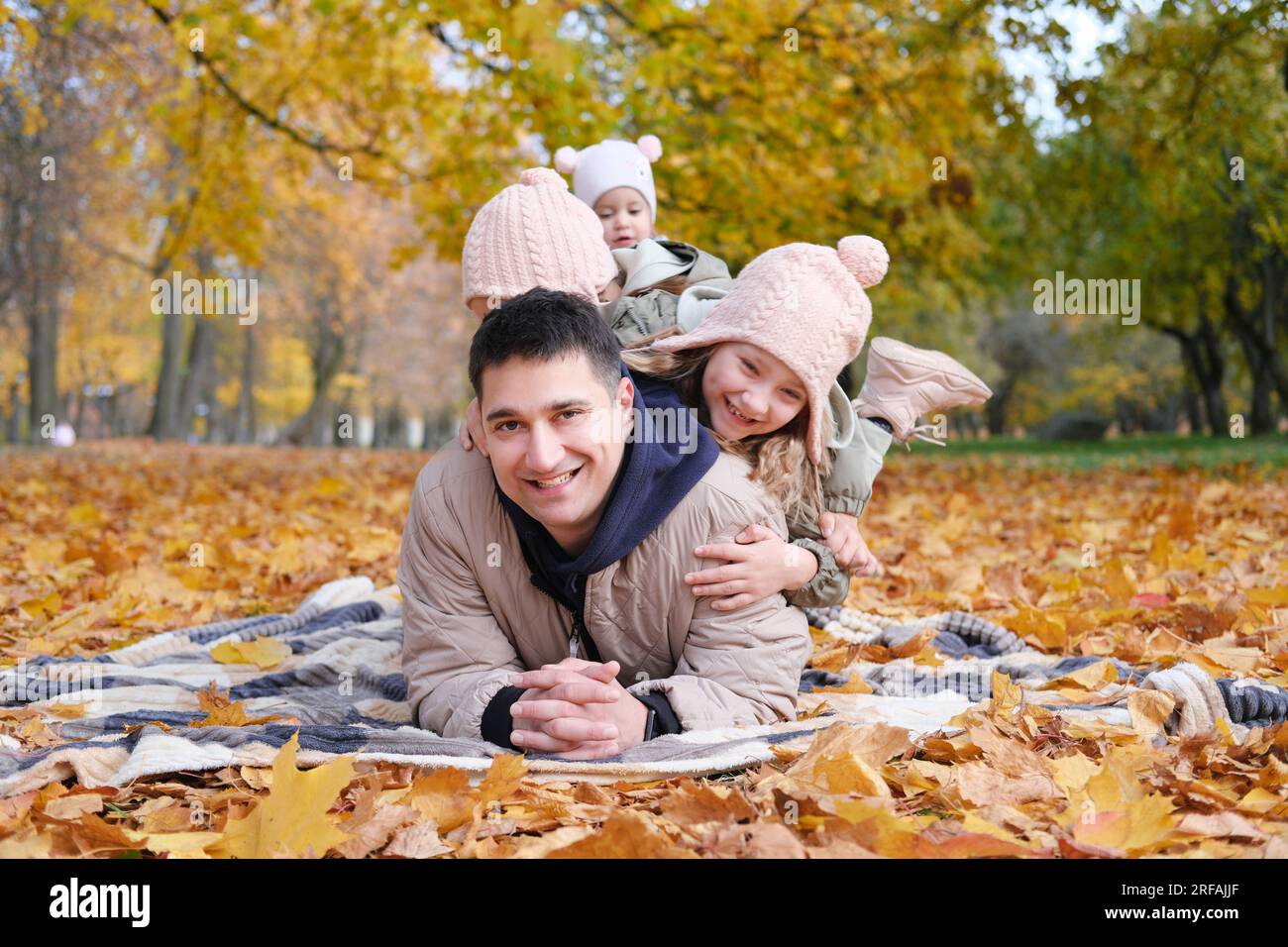 Father with children lying down on a blanket making a human pyramid in ...