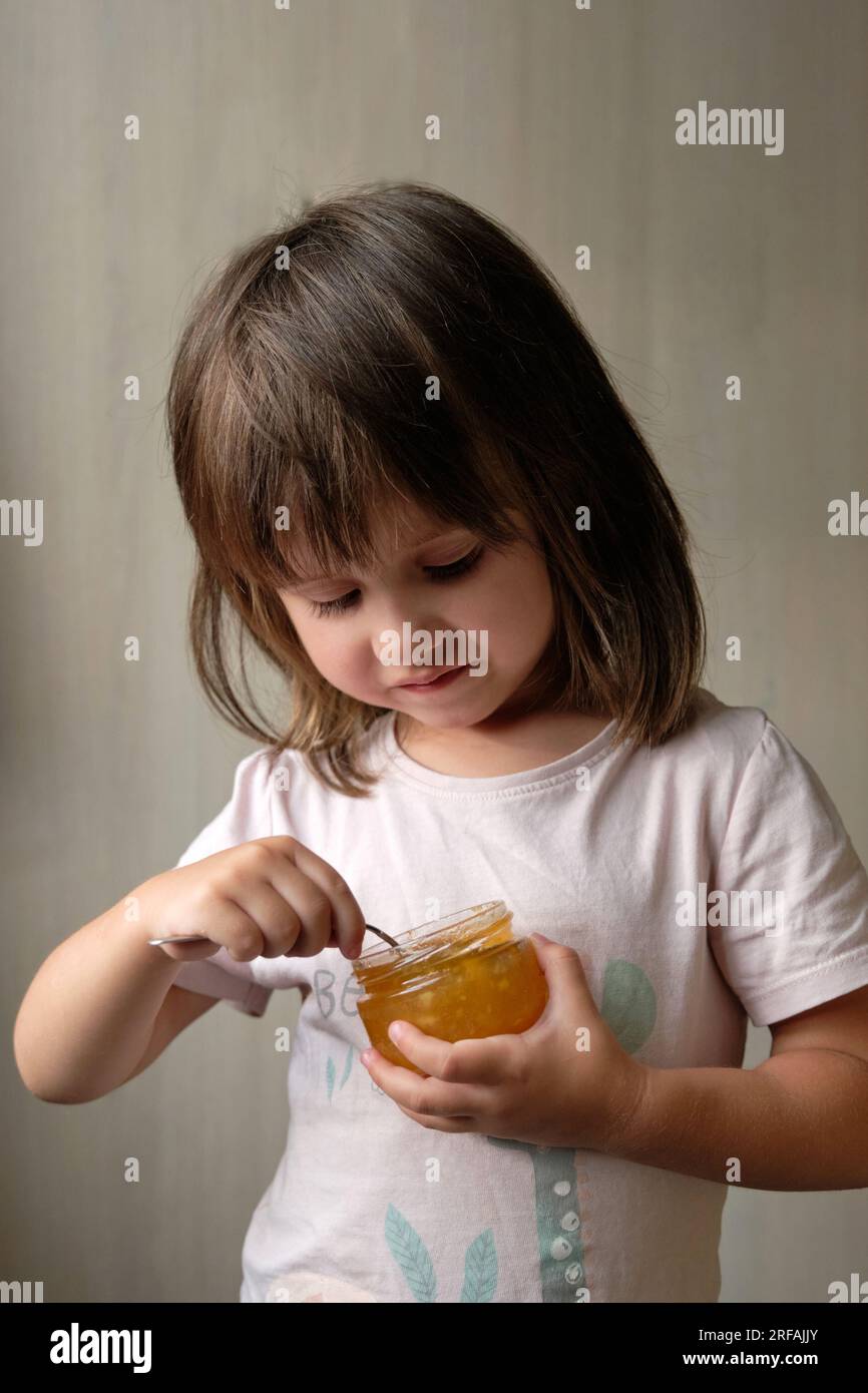 Adorable little girl eat dessert with metal spoon indoors. Kid eating ...