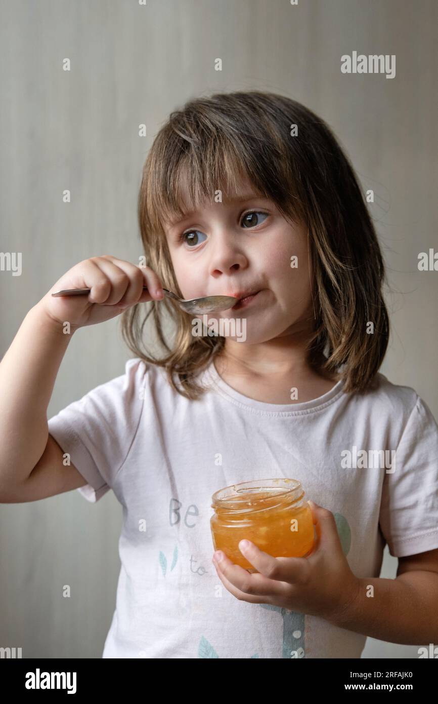 Adorable little girl eat dessert with metal spoon indoors. Kid eating ...