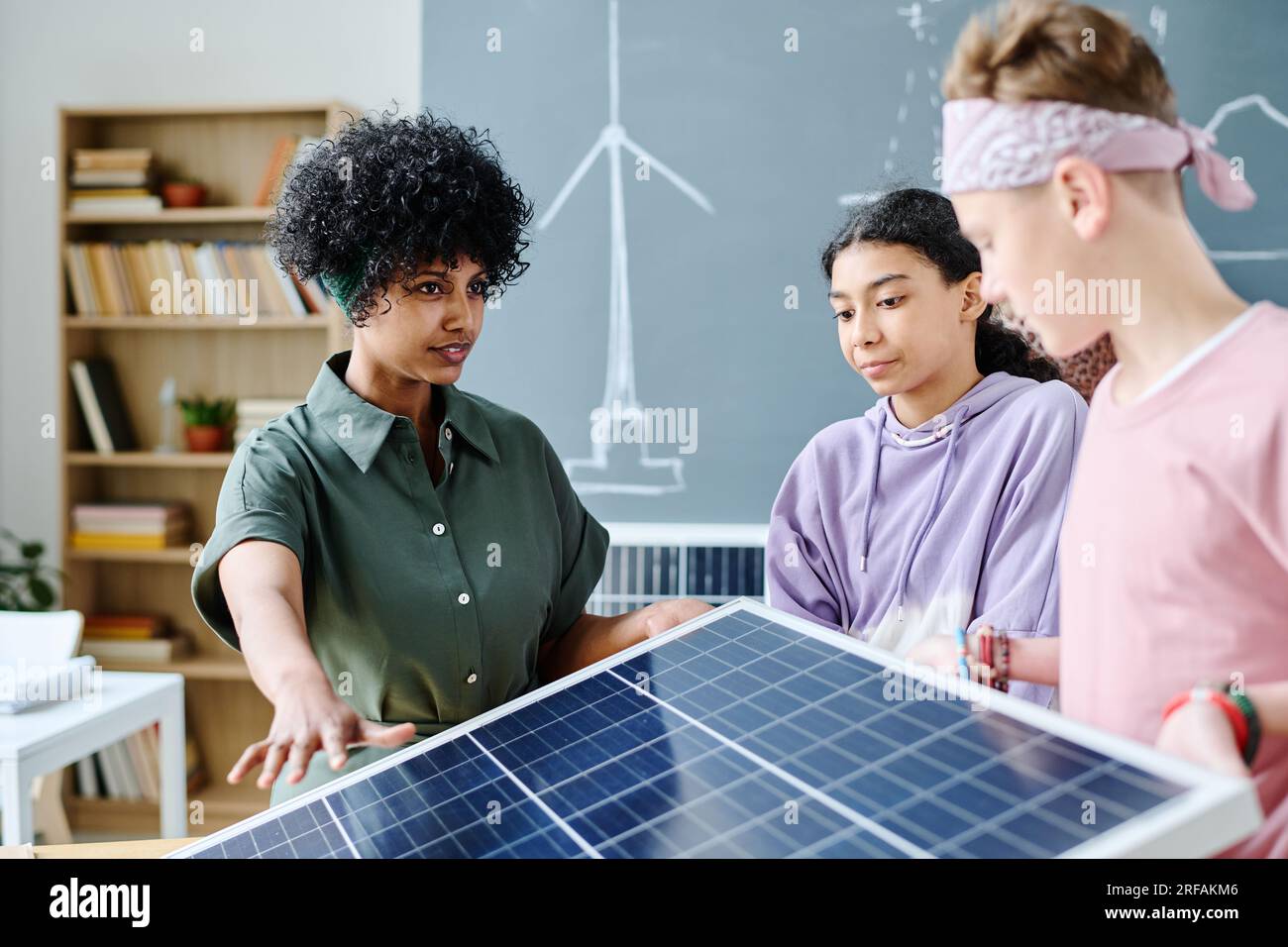 Teacher showing solar panel to students during lesson in classroom ...