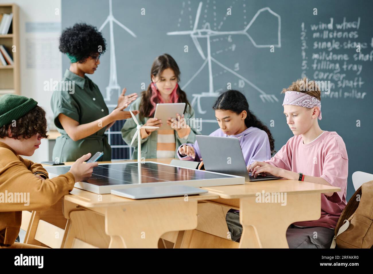 Group of students using gadgets to learn new technology with teacher ...