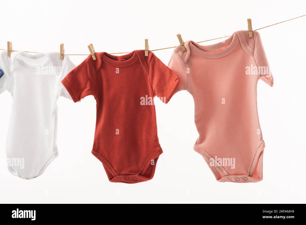 Three baby grows hanging from clothes line with pegs and copy space on ...