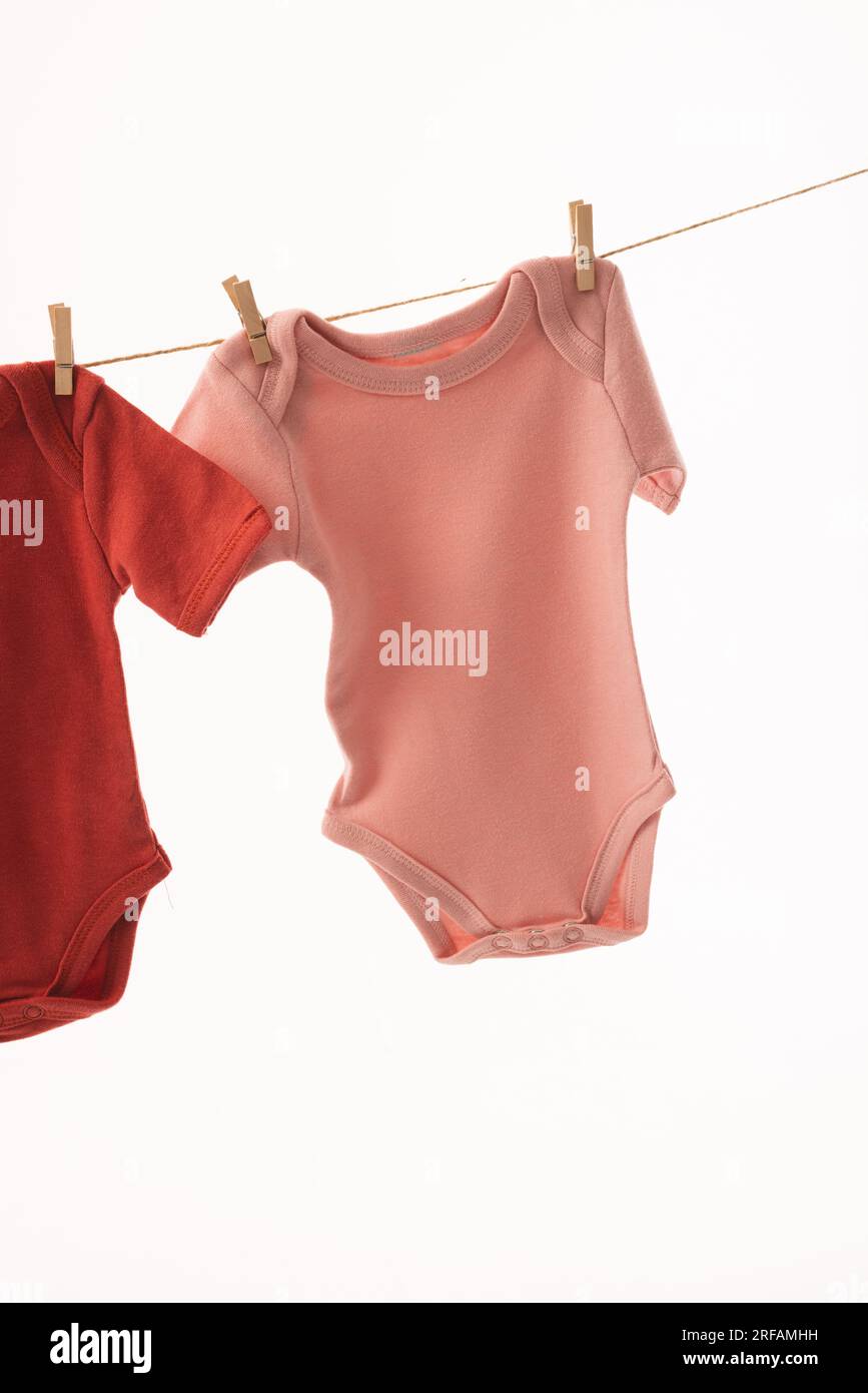 Two baby grows hanging from clothes line with pegs and copy space on ...