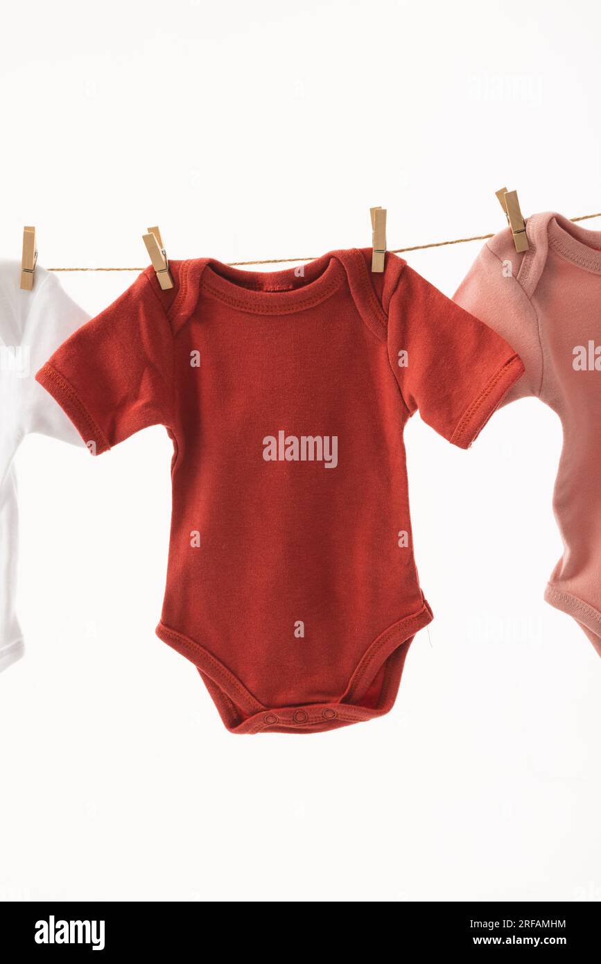 Three baby grows hanging from clothes line with pegs and copy space on ...