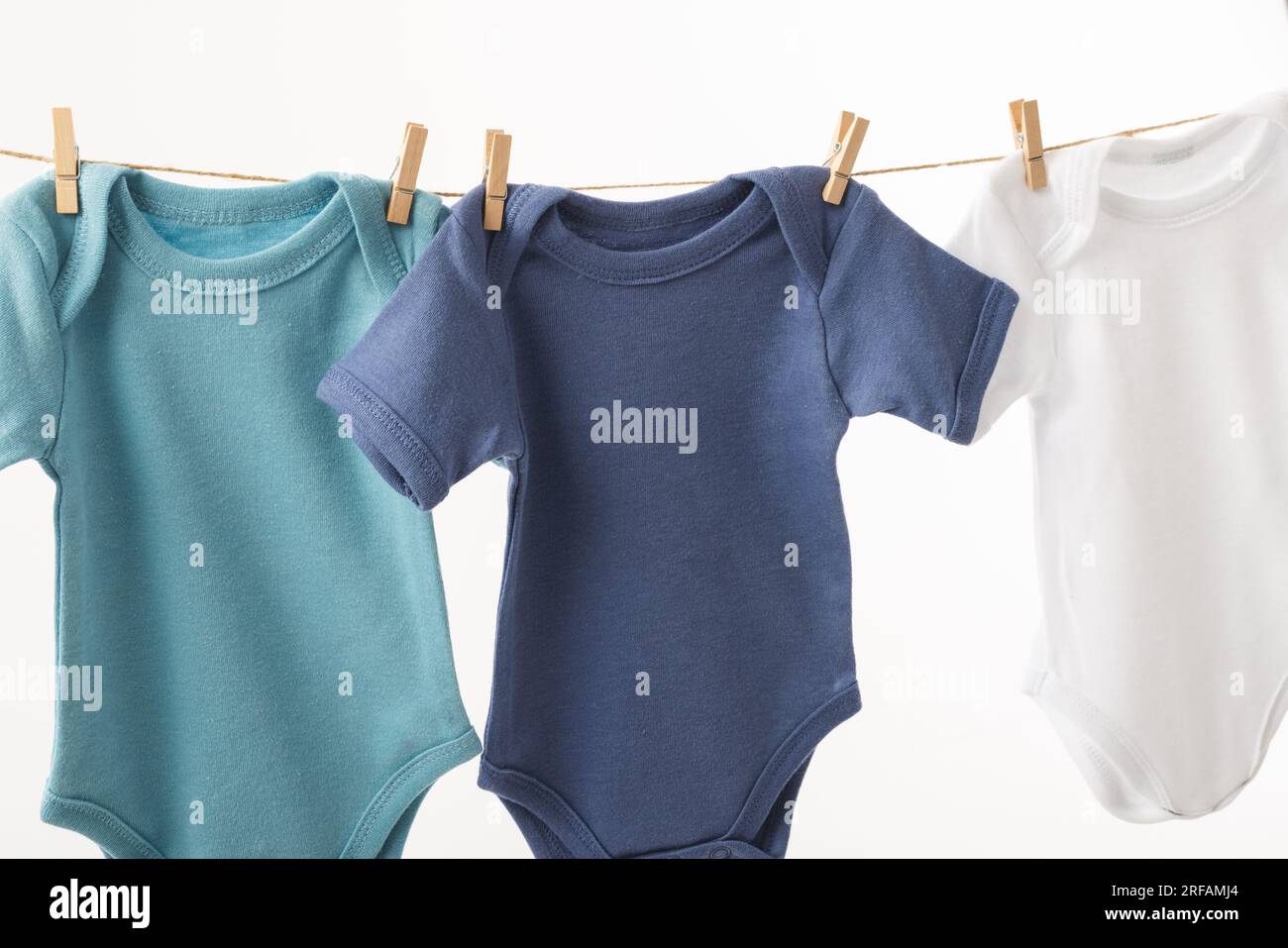 Three baby grows hanging from clothes line with pegs and copy space on ...