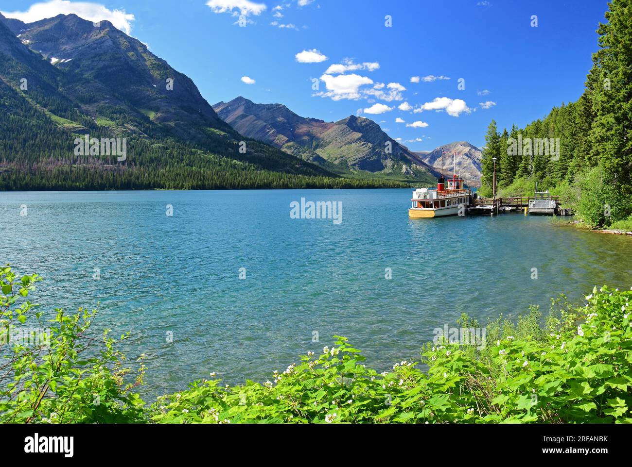 magnificent waterton lake, mountain peaks, and the boat and dock as ...