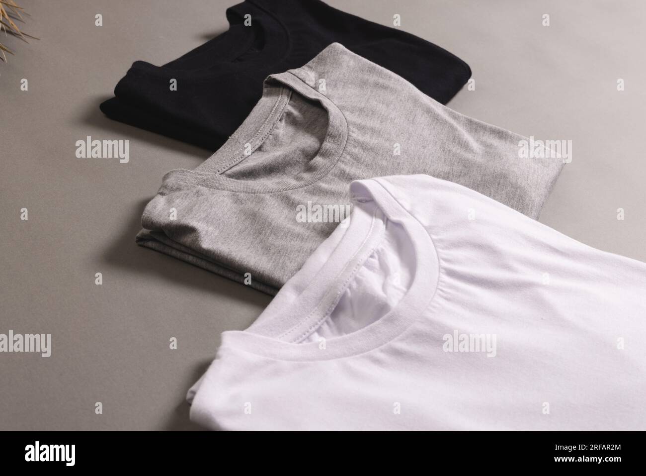 Three t shirts with copy space on grey floor background Stock Photo - Alamy