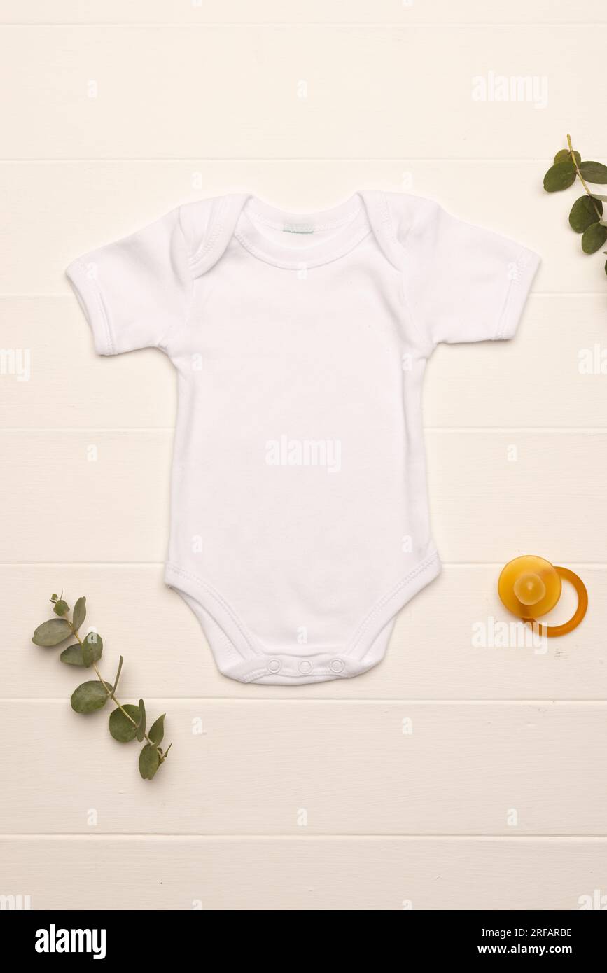 Flat lay of white baby grow and dummy with copy space on white ...
