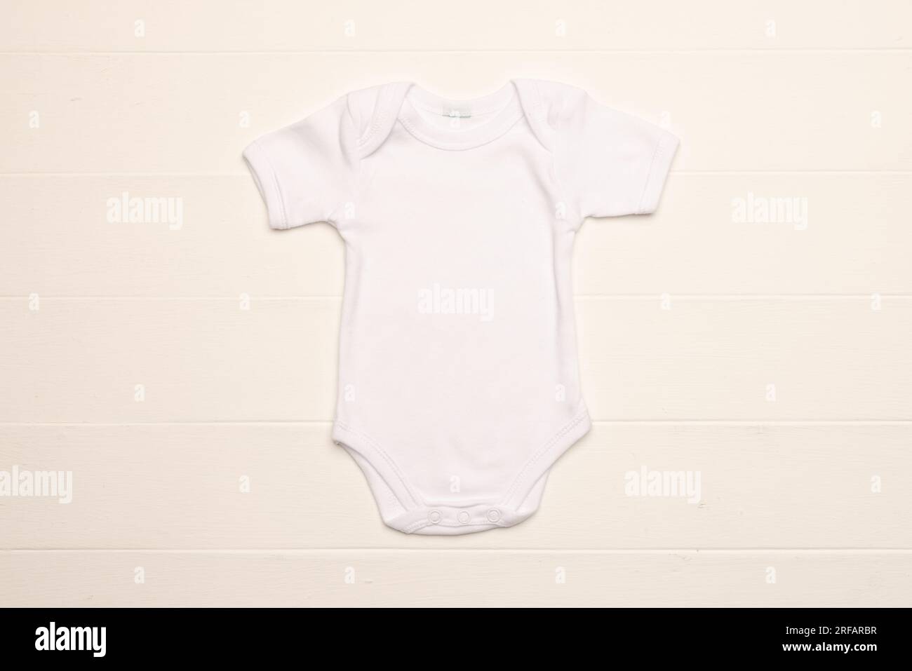 Flat lay of white baby grow with copy space on white board background ...