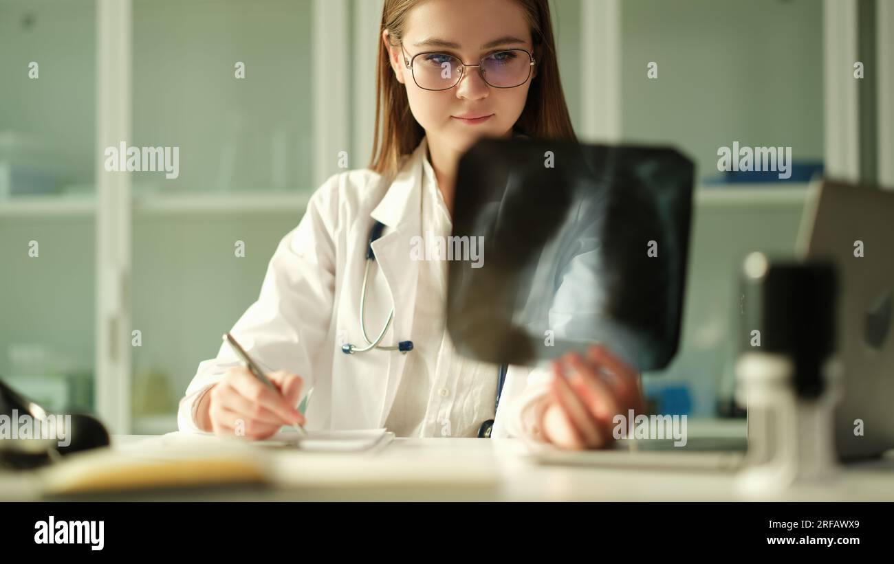 Concentrated woman surgeon traumatologist looks at x-rays examines ...