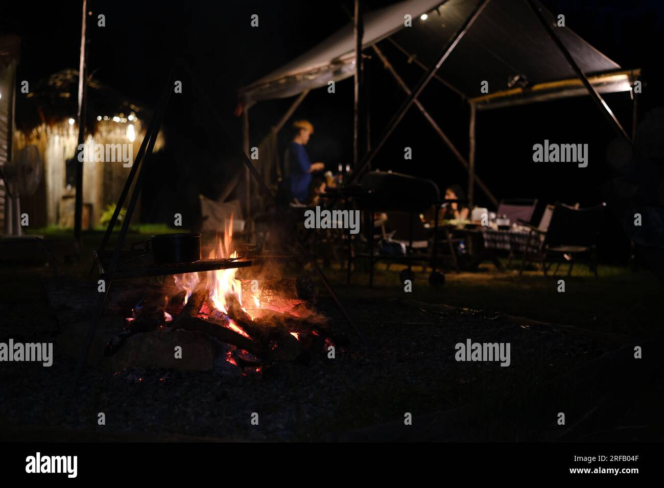 Bonfire near camping tent outdoors in evening and group of people ...