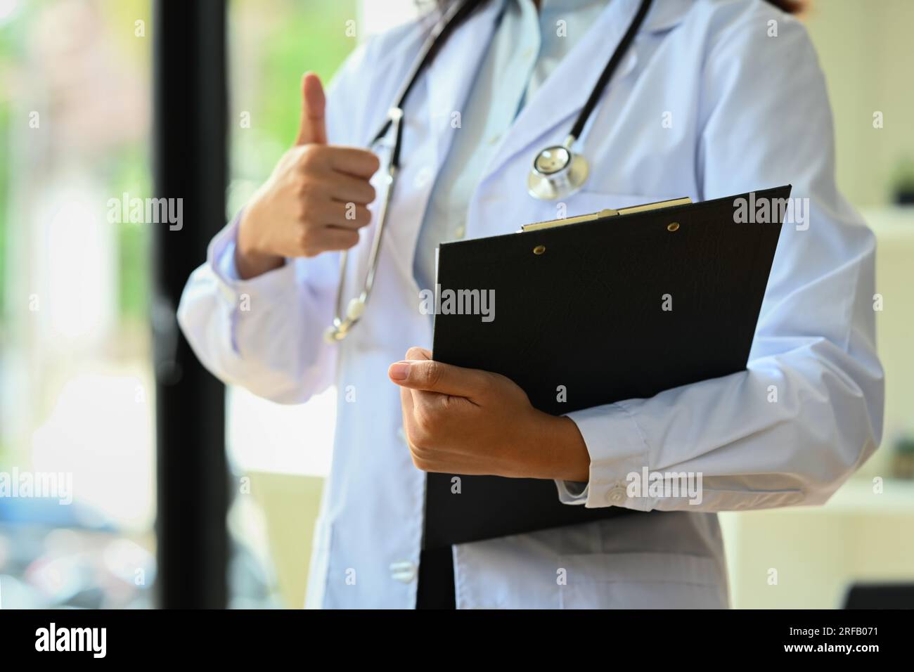 Doctor dressed in white overall with stethoscope holding clipboard and ...