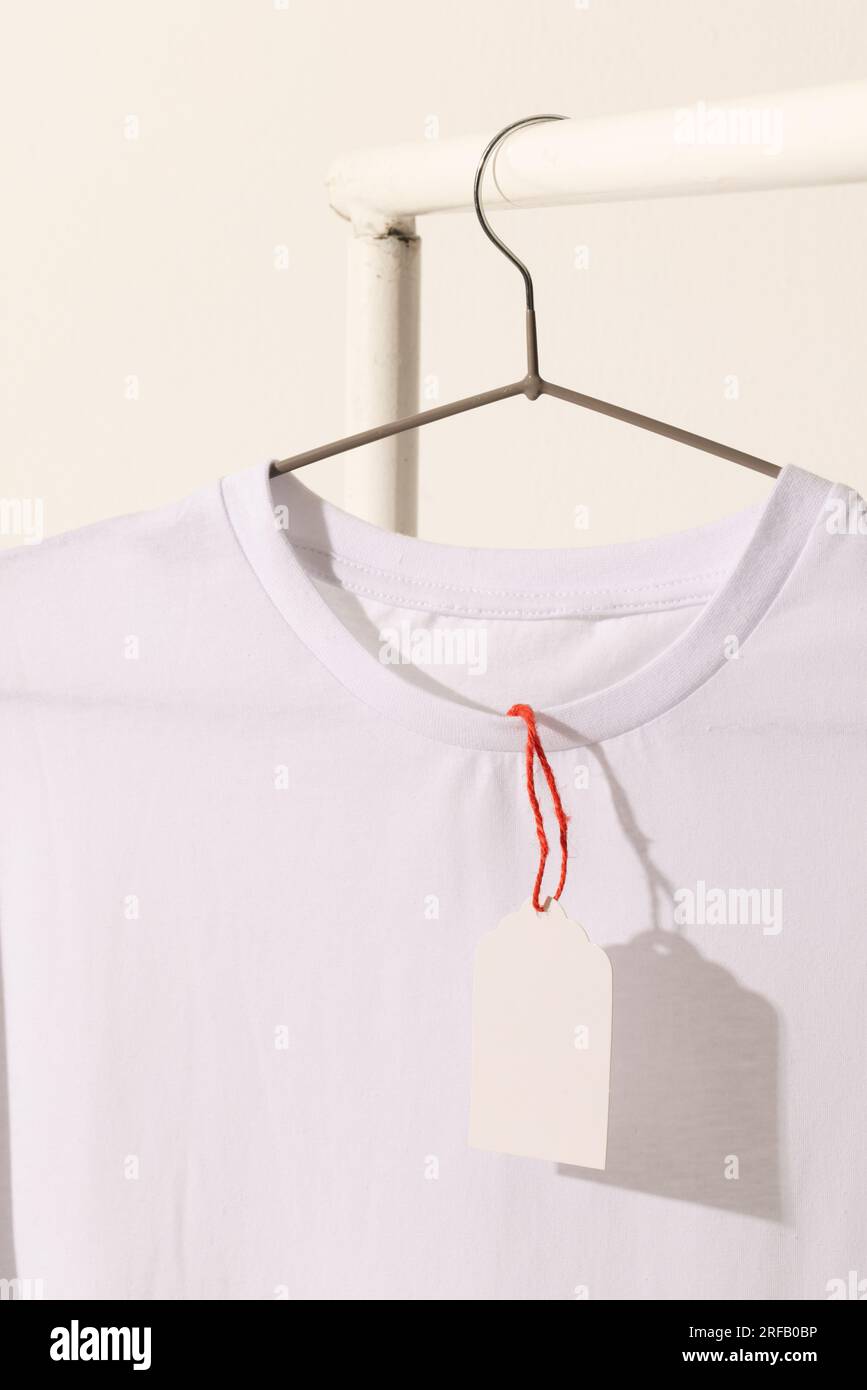 White t shirt with tag hanging from clothes rack with copy space on ...