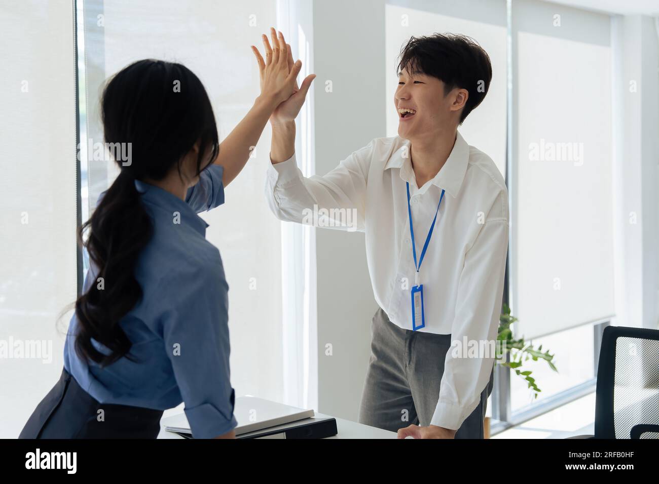 happy Asian male office worker standing gives high fives to a female ...