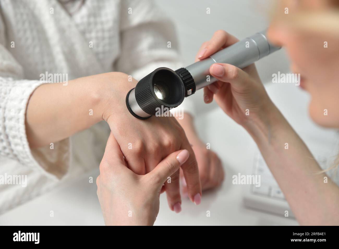 Beautician examine the skin on the female hand with a dermatoscope ...
