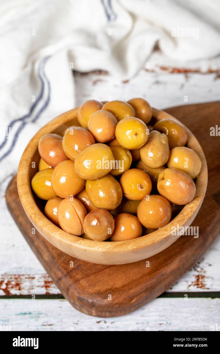 Big green olive at wooden bowl. Olives on a white wood background ...