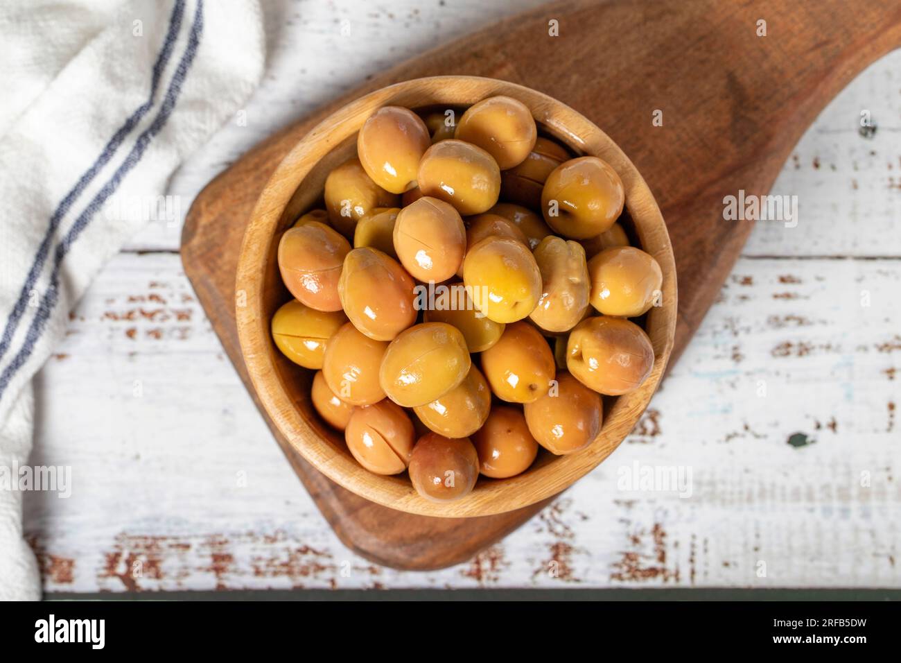 Big green olive at wooden bowl. Olives on a white wood background ...